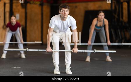 Slender guy trains muscles of arms and back using barbell and ...