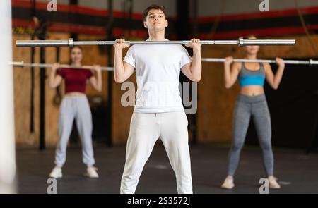 Slender guy trains muscles of arms and back using barbell and ...