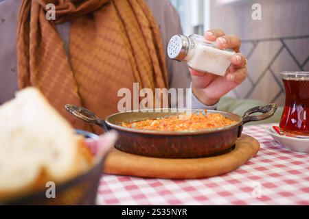 woman pouring salt on Turkish Menemen omelet in a frying pan Stock ...
