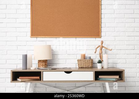 Burning candles and wooden mannequin on end table near grey wall Stock ...