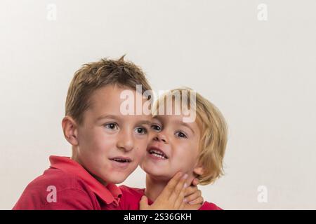 Siblings whisper a secret in each other's ears Austria Stock Photo - Alamy