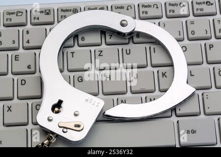 Handcuffs lie on the keyboard of a computer. Symbolic photo for ...