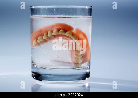 A dental prosthesis is cleaned in a glass of water. Proper hygiene ...