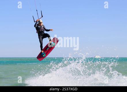 Man with surfboard kiteboarding on sea during sunny day Stock Photo - Alamy