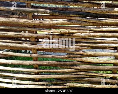 Rustic fence made with tree branches and wooden posts with a small roof ...