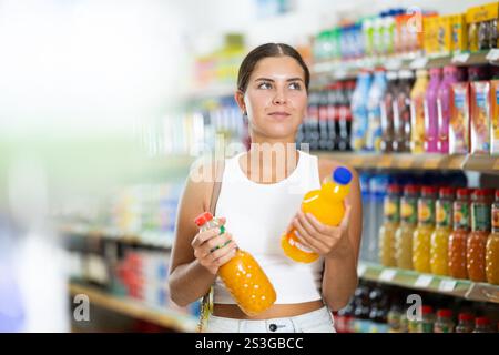 Young woman choosing soda in grocery store Stock Photo - Alamy