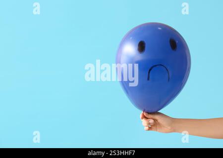 Hand holding balloon with drawn sad face on blue background Stock Photo ...