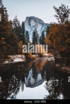 HALF DOME is reflected in the MERCED RIVER during the fall season ...