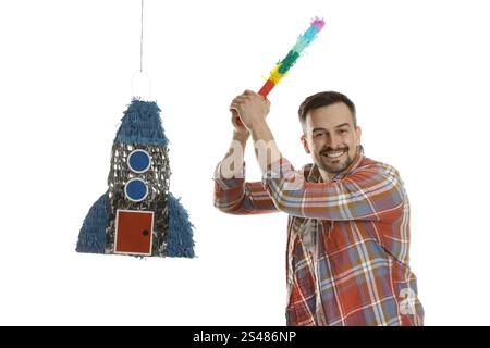 Happy man hitting rocket shaped pinata with stick on white background ...
