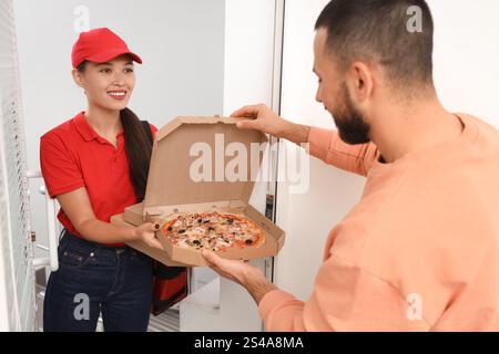 Female courier giving ordered pizza to client Stock Photo - Alamy