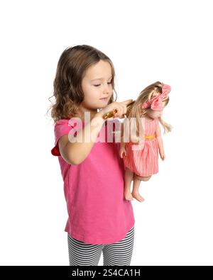 Cute little girl brushing doll's hair on white background Stock Photo ...