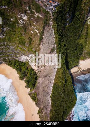 Aerial shot of steep, rocky steps descending a huge cliff to a tropical ...