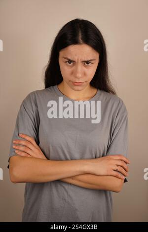 A young woman with furrowed brows displays an expression of seriousness ...