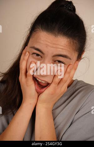 A woman places her hands on her cheeks, her wide-eyed expression ...