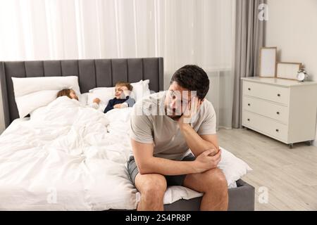 Overwhelmed father and his naughty children on bed at home Stock Photo ...