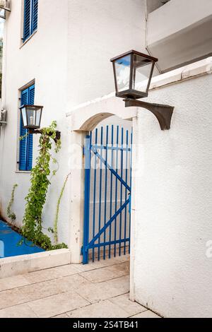 Painted blue gates in white wall with gas lamp at greek style Stock ...