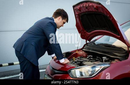 Young caucasian businessman trying to fix crashed down car engine Stock ...