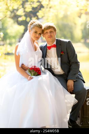 Bride and groom sitting on bench in park Stock Photo - Alamy