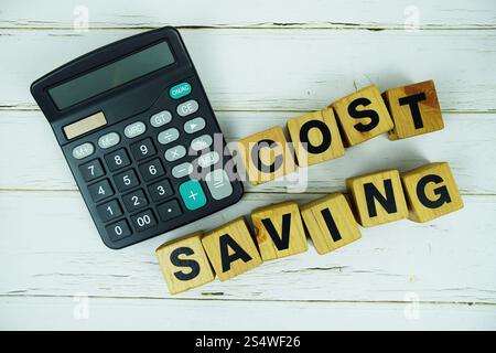 Cost Savings alphabet letters with calculator top view on wooden ...