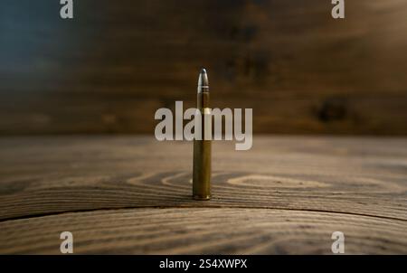 Closeup photo of one bullet standing on old wooden desk Stock Photo - Alamy