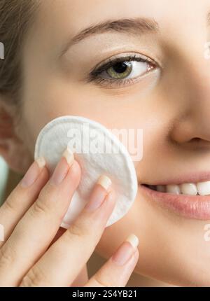 Makeup removal. A beautiful young woman wiping the make-up off her face ...
