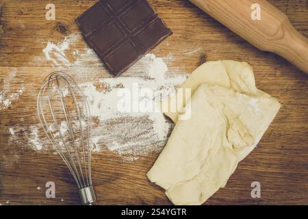 Wooden rolling pin lying on a yellow dough on a gray table sprinkled ...