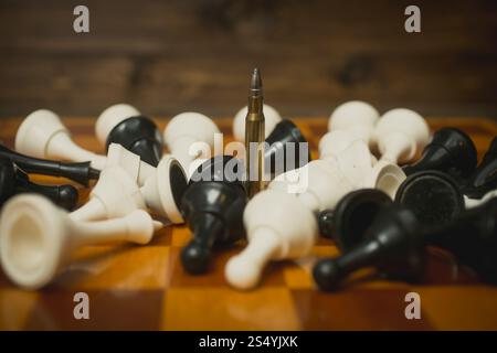 One riffle bullet on chessboard among lying chess pieces. Concept of ...