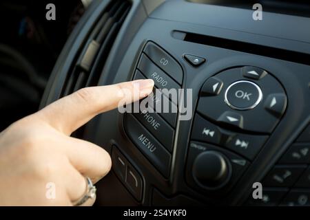 Woman turns on media radio in a car Stock Photo - Alamy