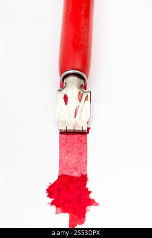 red dip pen draws a red line on sheet of paper by wide nib close up ...