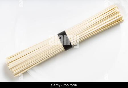 bunch of dried round Udon noodles from wheat flour on white plate Stock ...