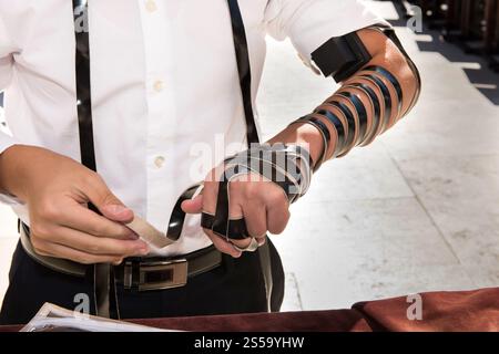 A Jewish man wraps the black leather straps of his tefillin around his ...