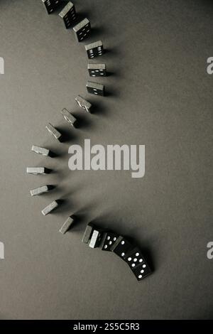Black dominoes chain on a dark table background. Domino effect concept ...
