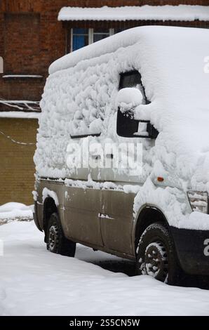 A closeup of a car covered with white fluffy snow in a backyard in ...