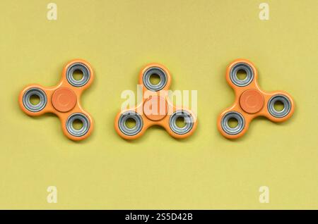 Many orange fidget spinners lies on texture background of fashion ...