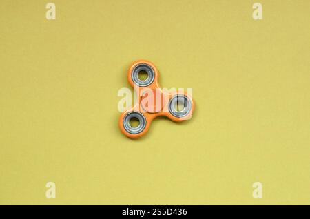 orange fidget spinner lies on texture background of fashion pastel ...