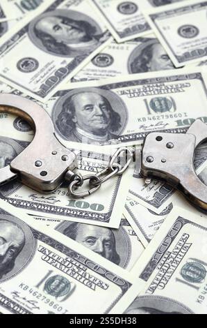 Police handcuffs lie on a lot of dollar bills. The concept of illegal ...