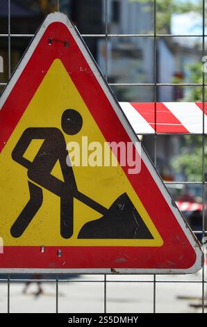 The warning sign "under construction" is attached to a metal mesh fence ...