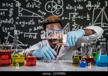 Scientists mix red and orange chemicals in a glass at the laboratory ...