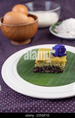 Black sticky rice and custard on a banana leaf in a white plate with ...