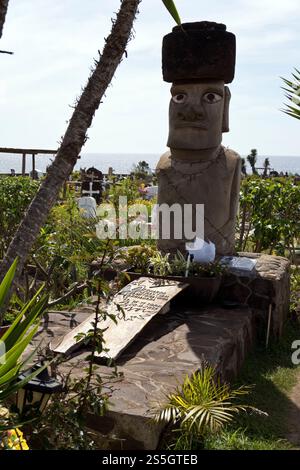 A Moai on a grave in the Hanga Roa cemetery display Christian and ...