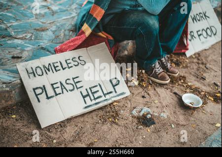 a man sitting beggars with homeless please help message. Selective ...