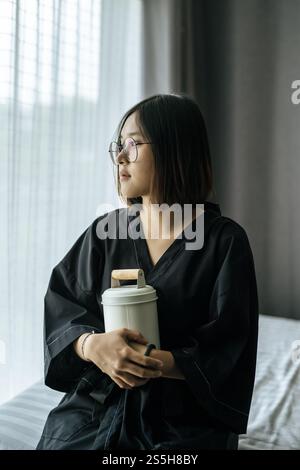 The woman wears a black robe and hugs tiffin and looks outside Stock ...