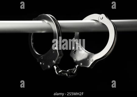 Metal chain handcuffs on pipe against black background, closeup Stock ...