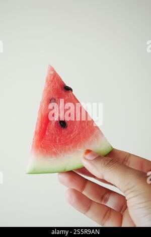fresh red watermelon slice held by hand with ripe watermelon on wooden ...