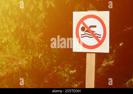 A pillar with a sign denoting a ban on swimming. The sign shows a ...