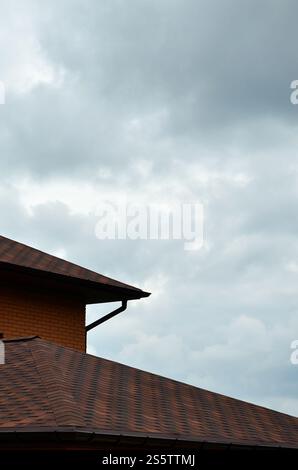 New roof with red shingles against the blue sky. Tiles on the roof of ...