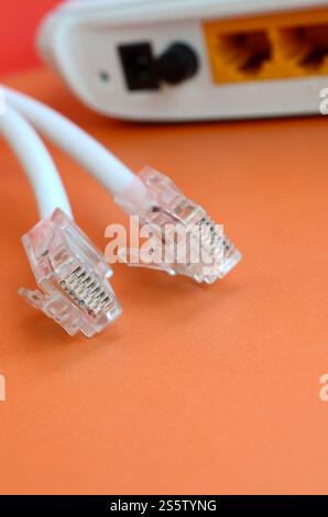 Internet router and Internet cable plugs lie on a bright orange ...