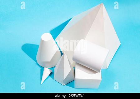 above view of different hand-crafted paper geometric forms on turquoise ...