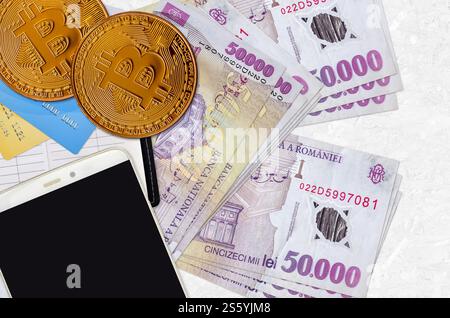 1 Romanian leu bills and golden bitcoins with smartphone and credit ...