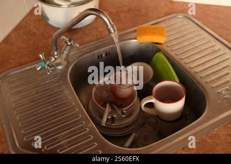 Stack of dirty dishes with food leftovers in the kitchen sink. Unwashed ...